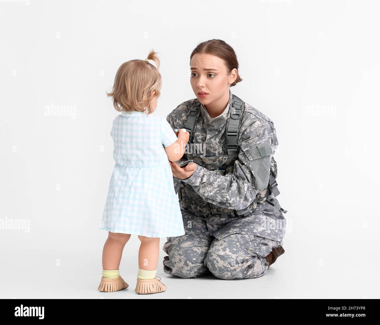 Sad female soldier with her baby girl on white background Stock Photo ...
