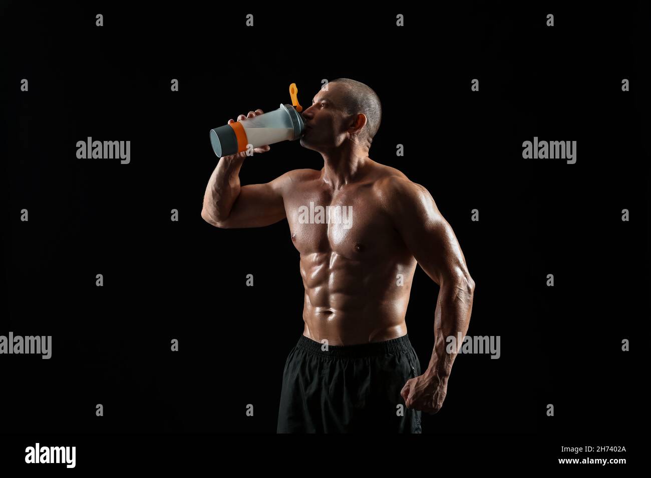 Male bodybuilder drinking protein shake on dark background Stock Photo ...