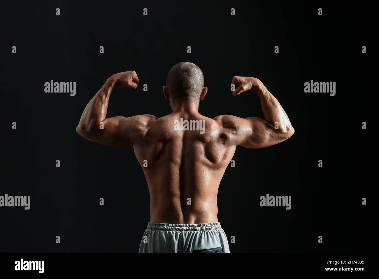 Male bodybuilder on dark background, back view Stock Photo - Alamy