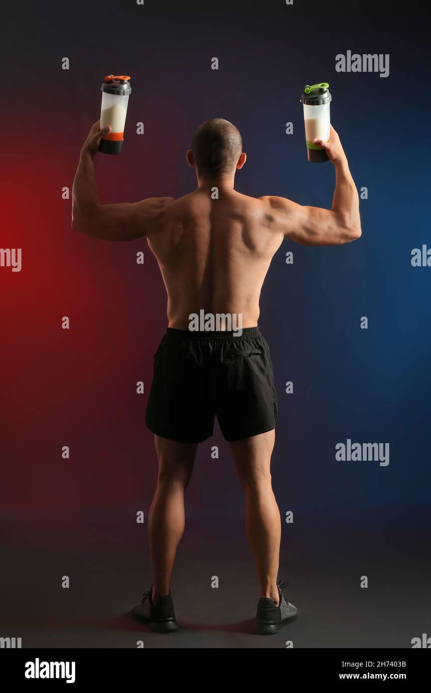 Male bodybuilder with protein shakes on dark background, back view ...