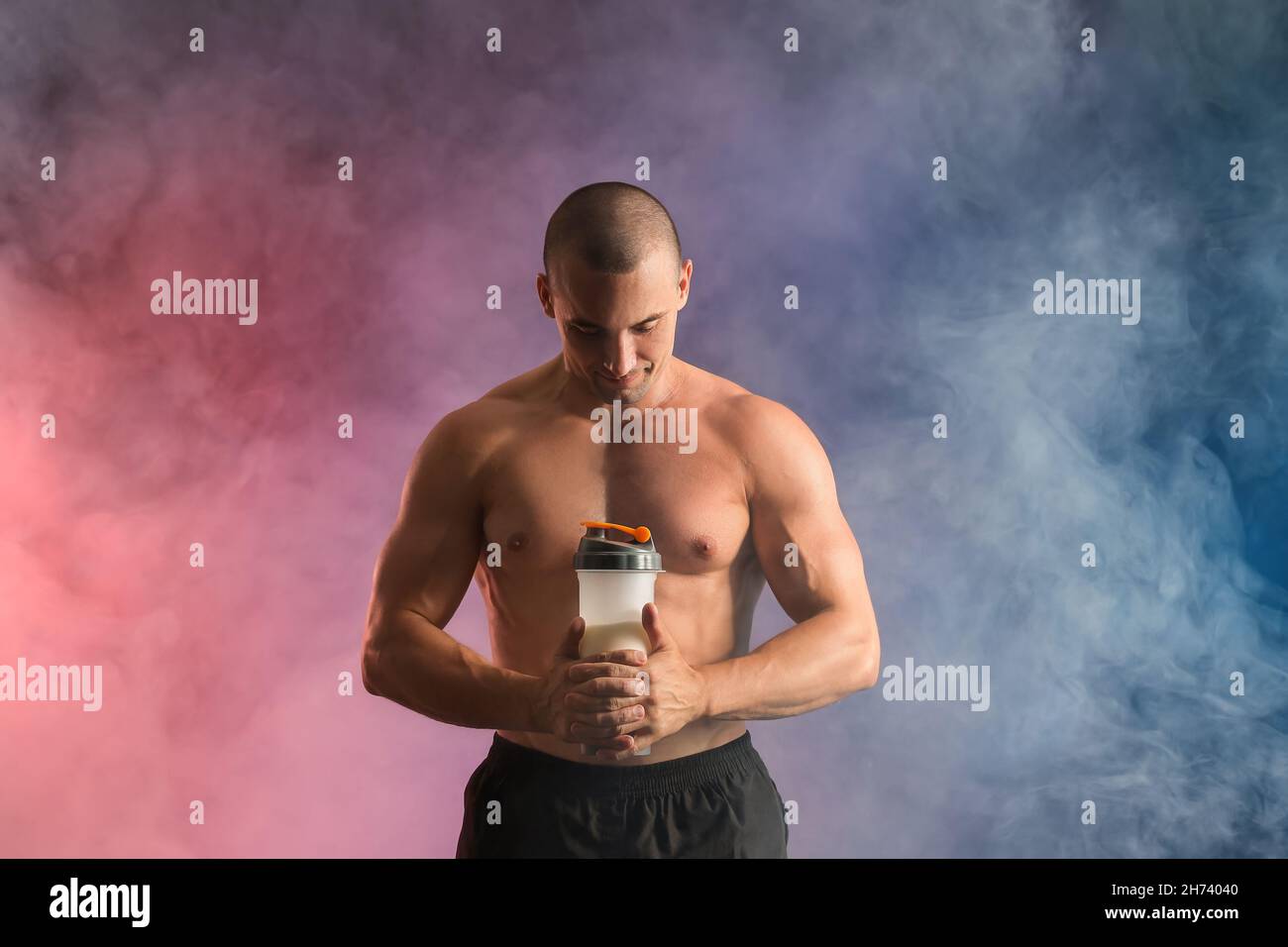 Male bodybuilder with protein shake in smoke on color background Stock ...