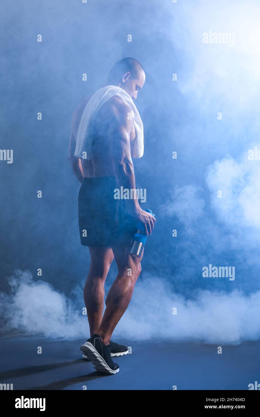 Male bodybuilder with protein shake in smoke on dark background Stock ...