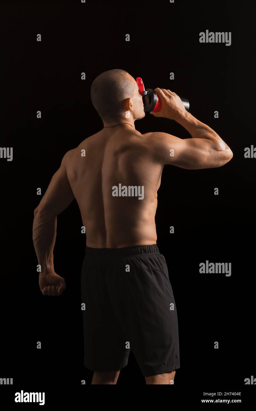 Male bodybuilder drinking protein shake on dark background Stock Photo ...