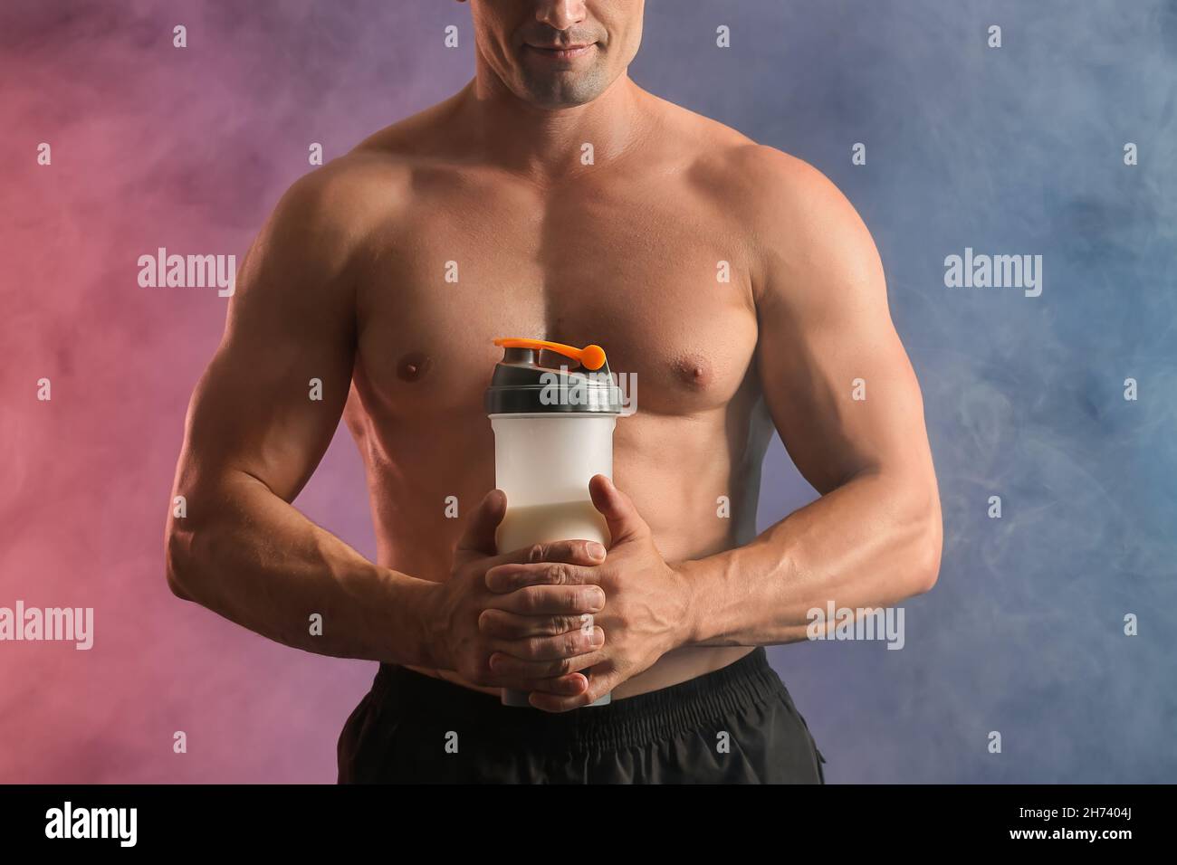 Male bodybuilder with protein shake in smoke on color background Stock ...