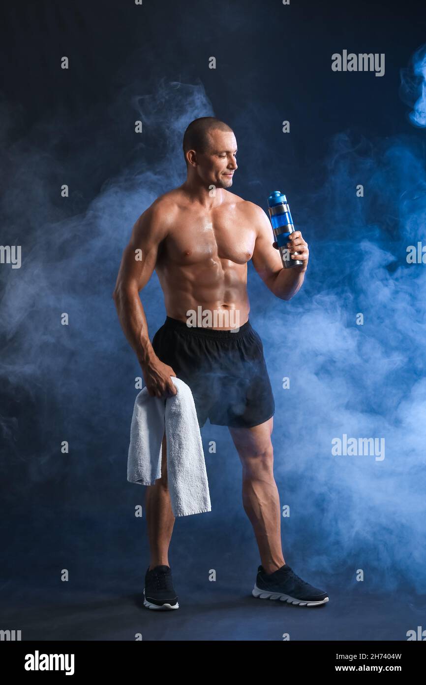 Male bodybuilder with protein shake in smoke on dark background Stock ...