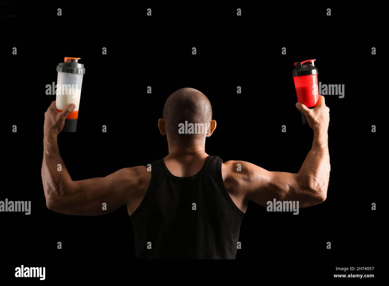 Male bodybuilder with protein shakes on dark background, back view ...