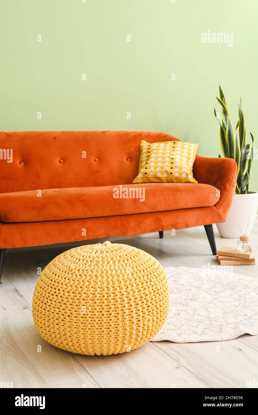 Sofa, pouf and houseplant near color wall Stock Photo - Alamy
