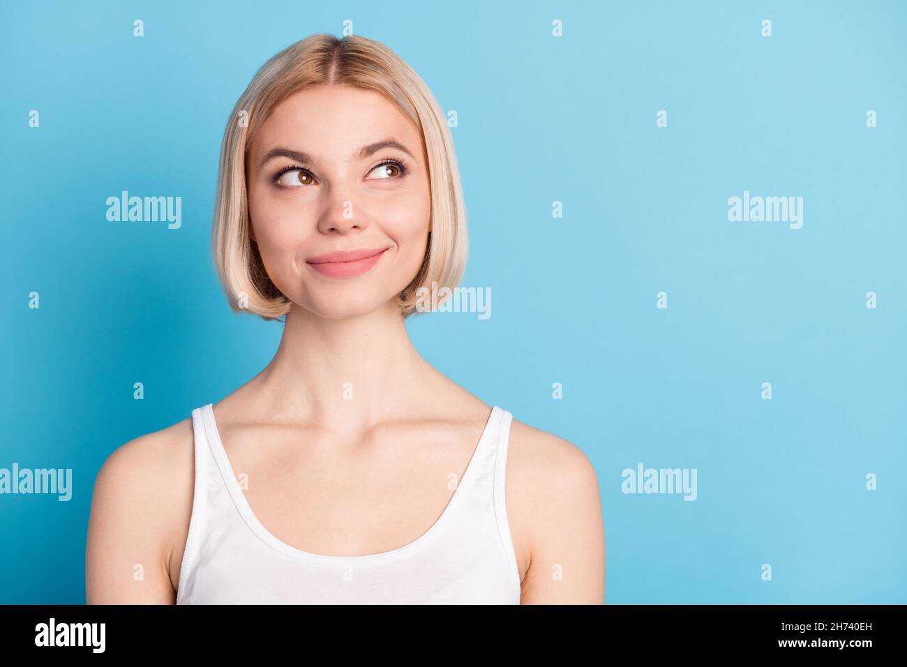 Photo of adorable lady smile look interested empty space thinking imagine isolated on blue color ...