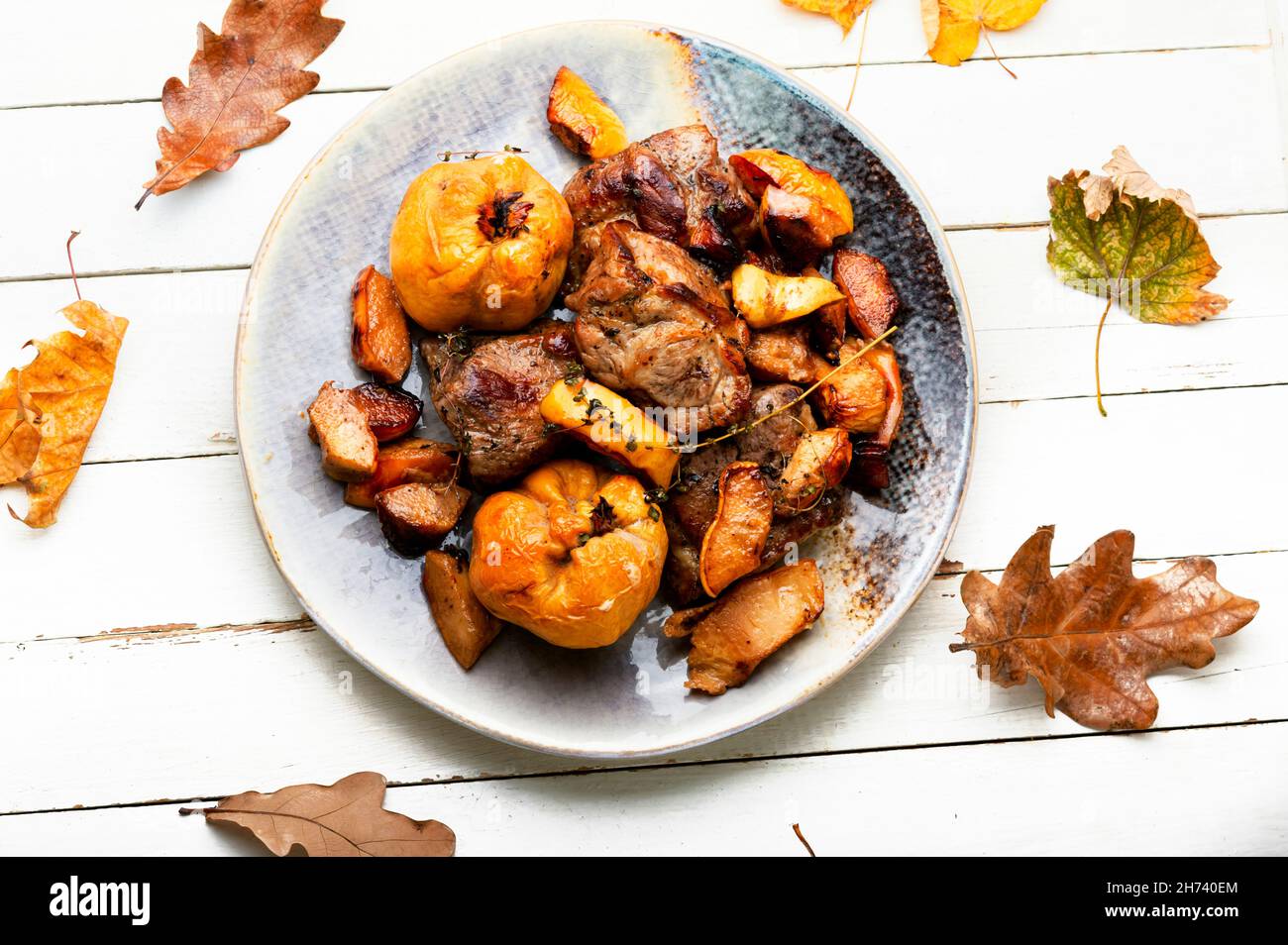 Delicious stewed meat with aromatic autumn quince on white background ...