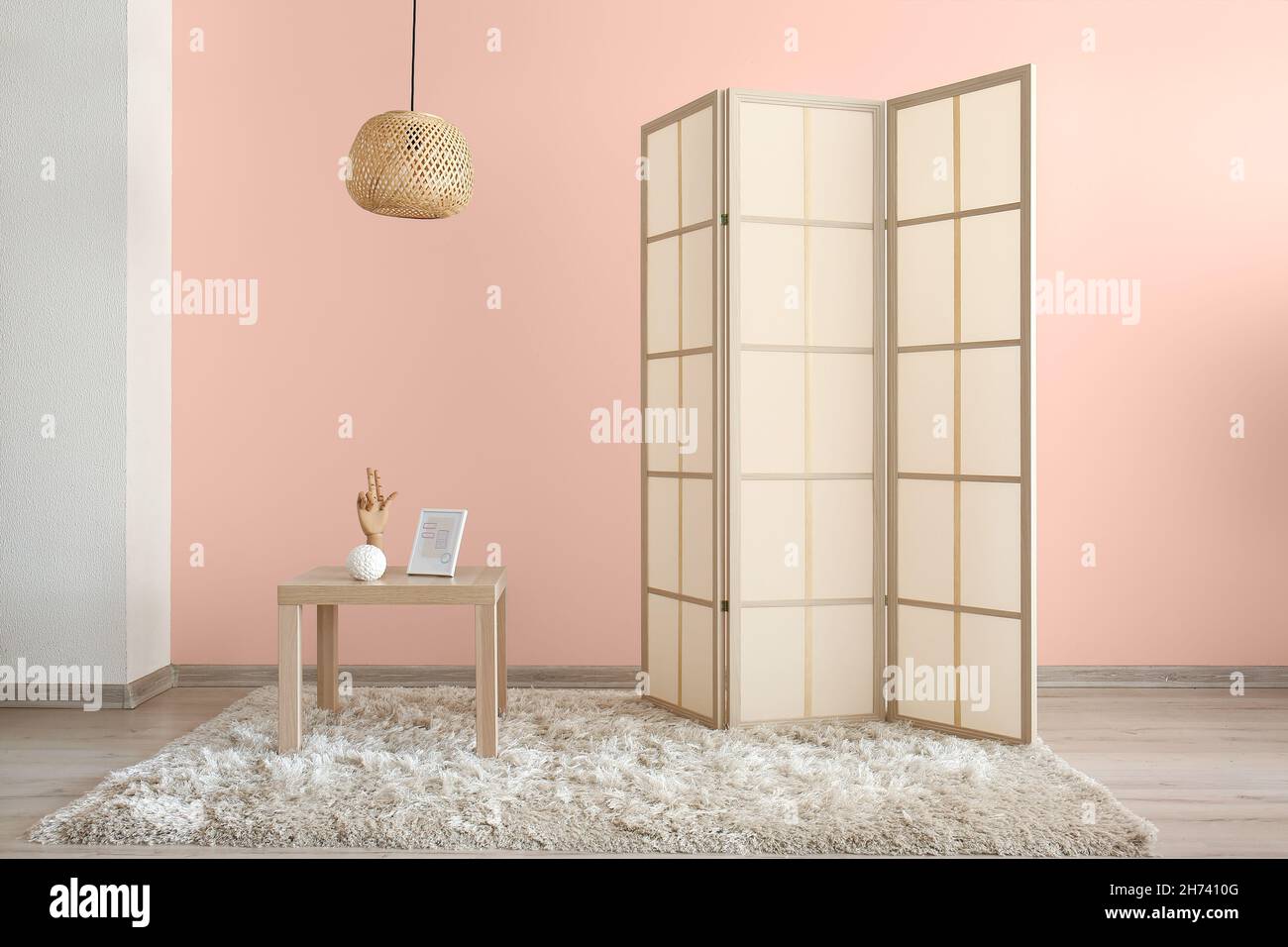 Stylish folding screen and small table near wall in room Stock Photo ...