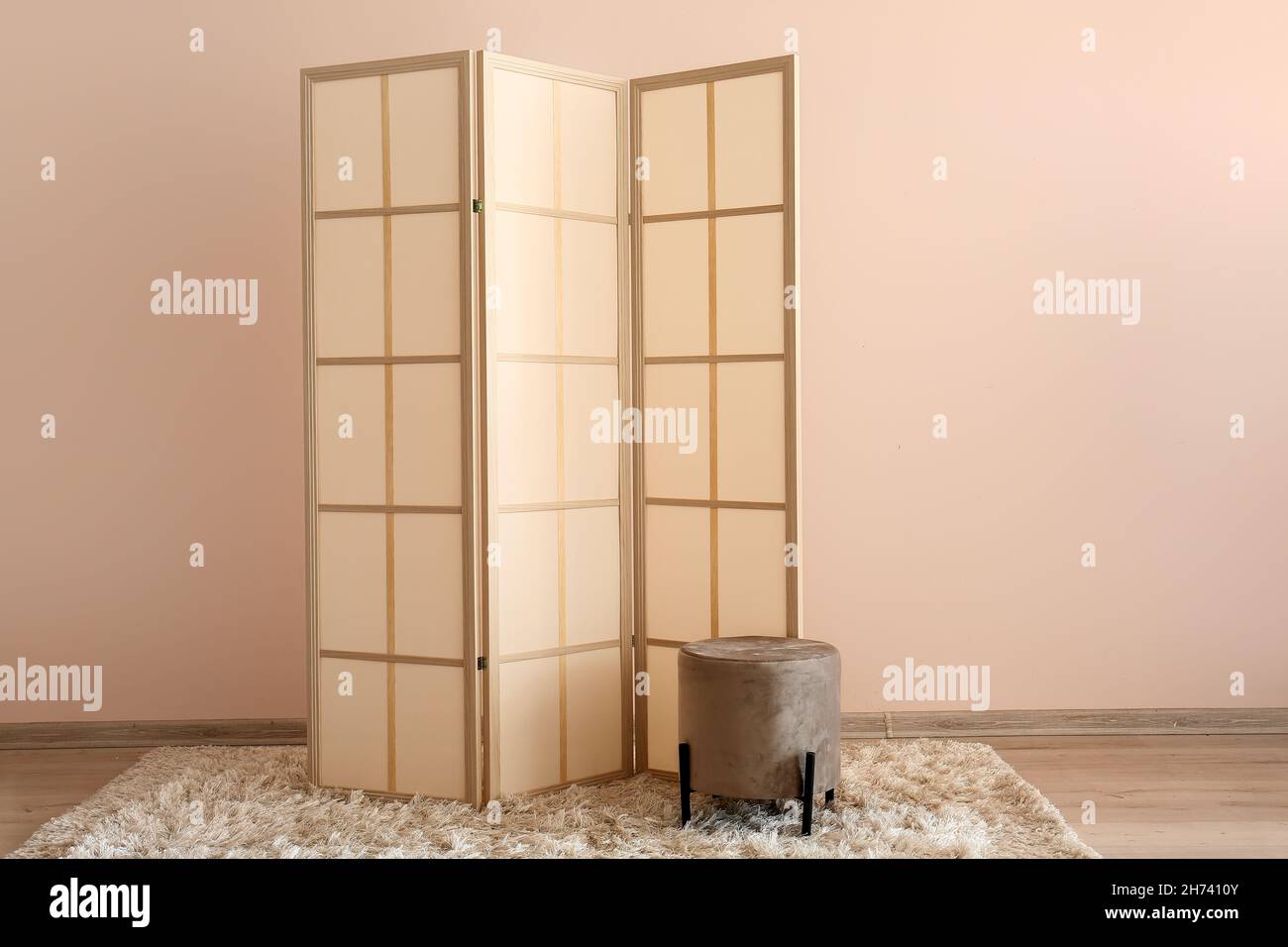 Stylish folding screen and ottoman near wall in room Stock Photo - Alamy