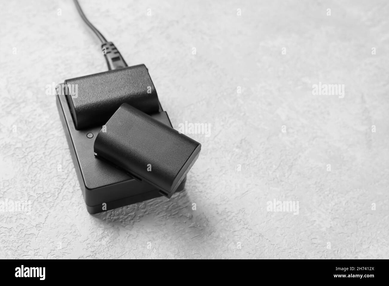 Camera batteries and charger on light table background Stock Photo - Alamy