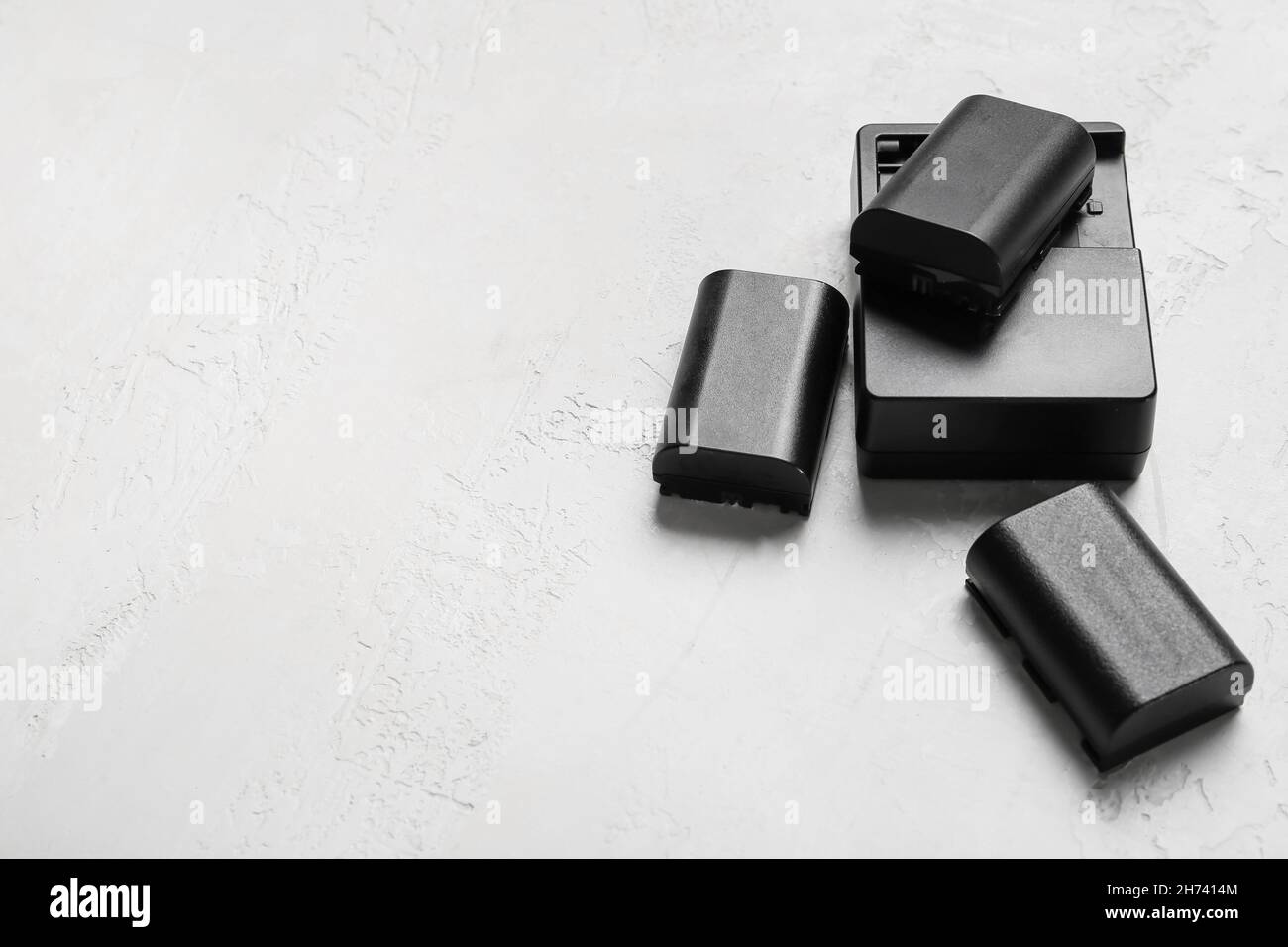 Camera batteries and charger on light table background Stock Photo - Alamy