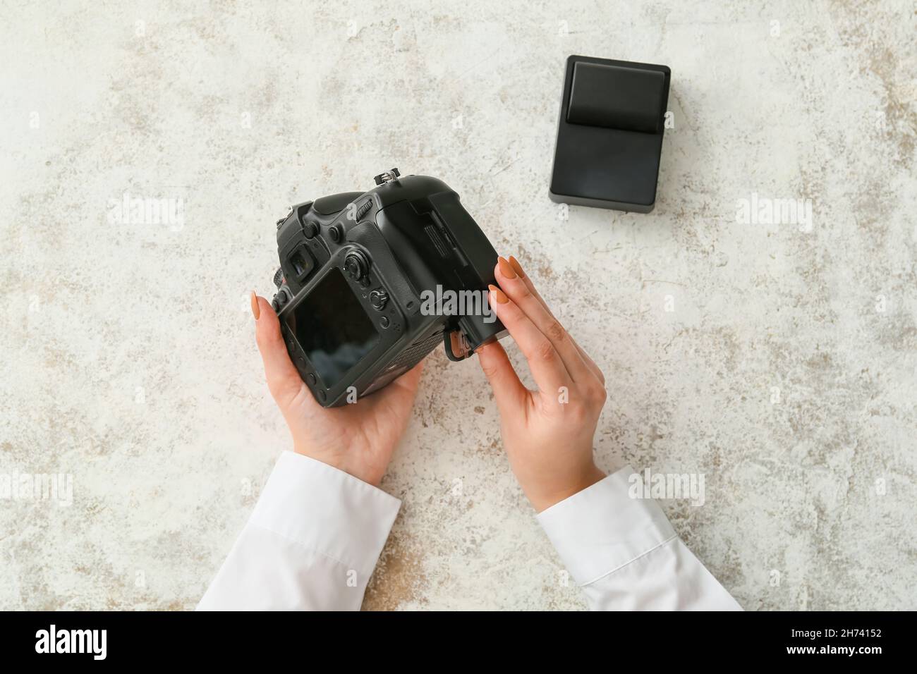 Woman putting battery in camera on light table background Stock Photo ...
