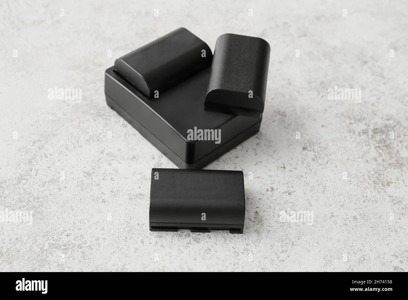 Camera batteries and charger on light table background Stock Photo - Alamy