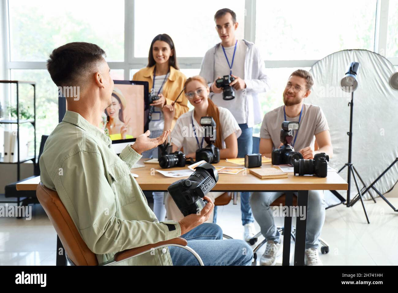 Professional photographer teaching young people in studio Stock Photo ...