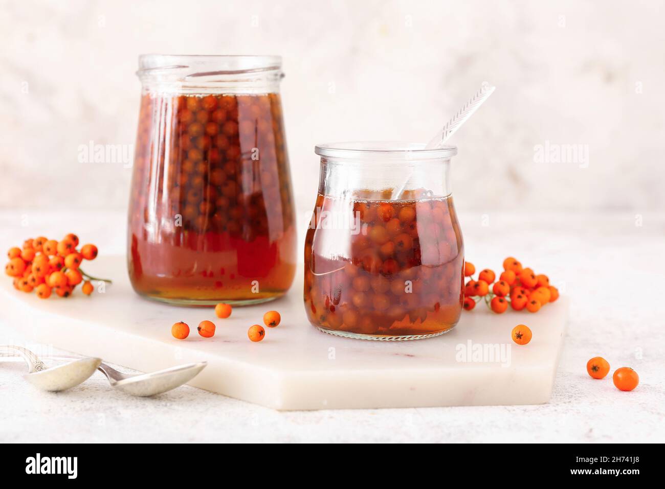 Glass jars with tasty rowan jam on light background Stock Photo - Alamy