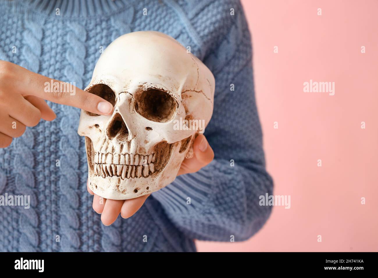 Young woman with human skull on color background, closeup Stock Photo ...