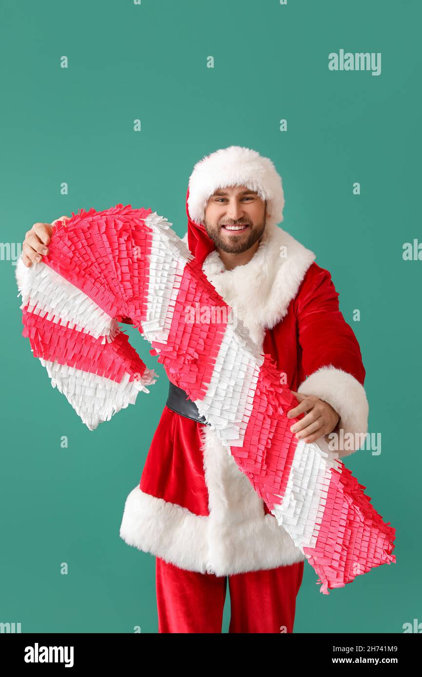 Santa Claus with candy cane pinata on green background Stock Photo - Alamy