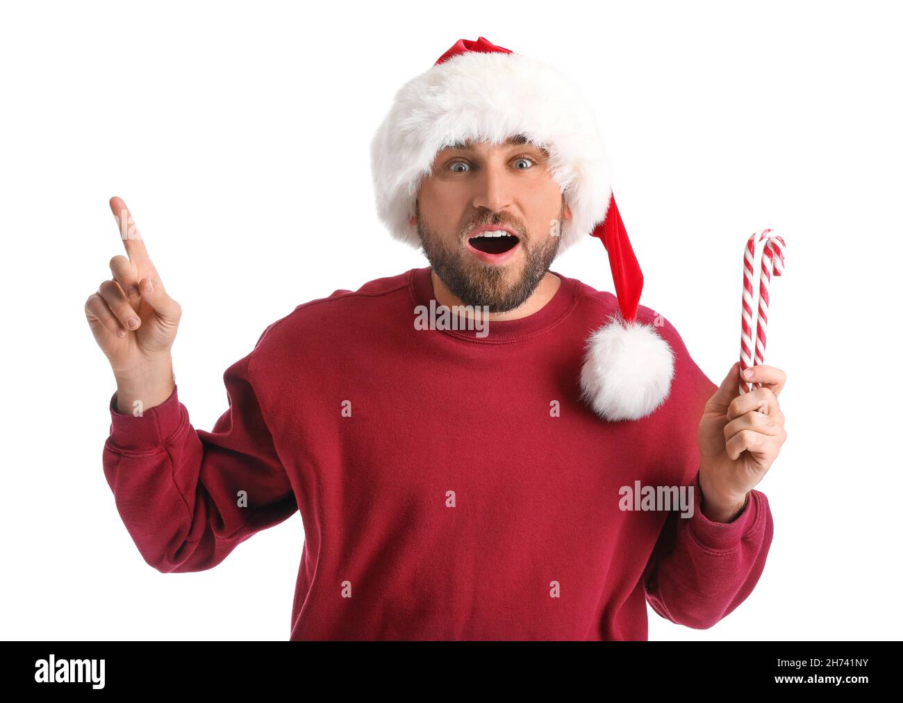 Surprised handsome man in Santa hat with candy canes pointing at ...