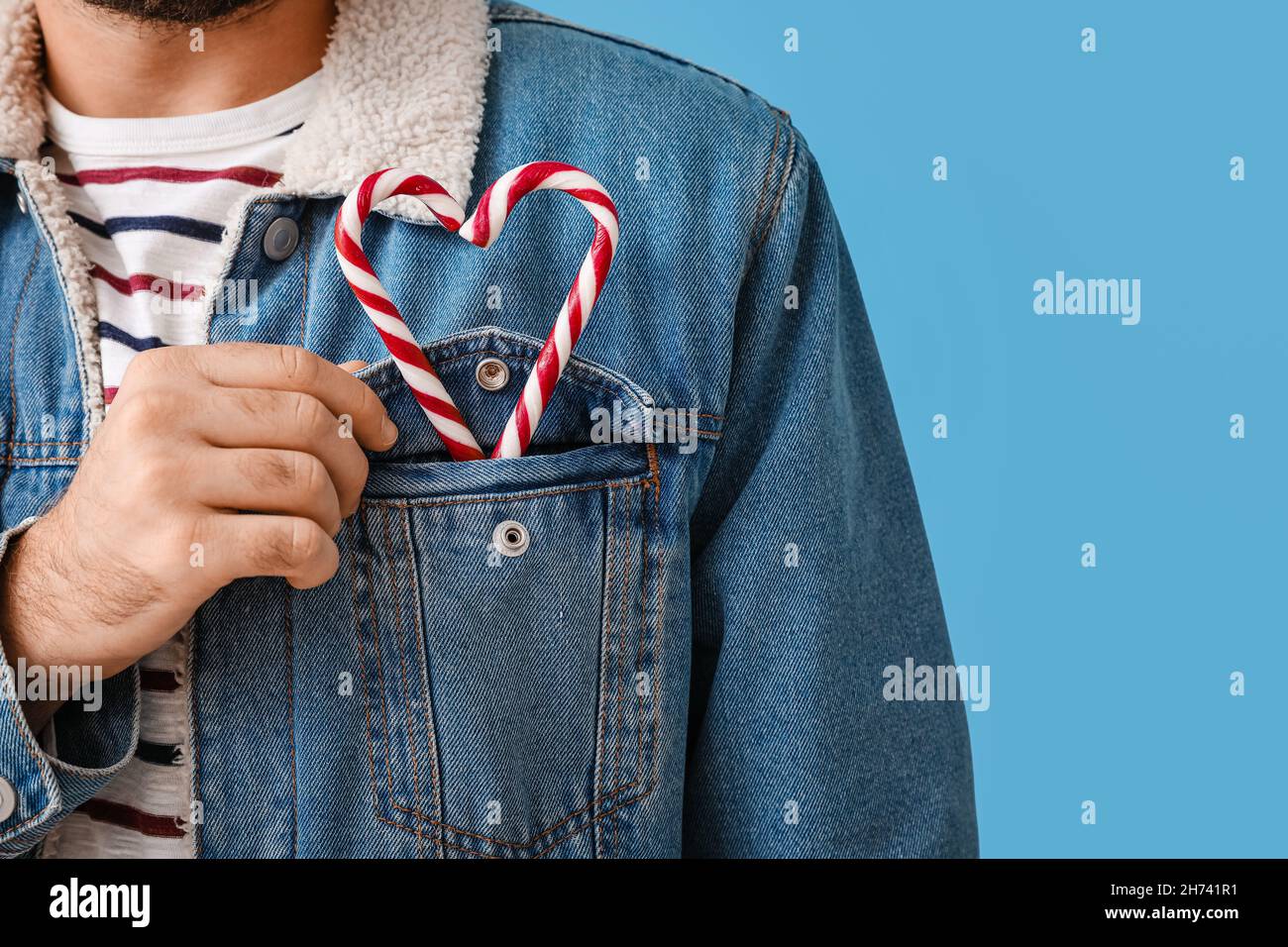 Handsome man in denim jacket with candy canes on blue background ...