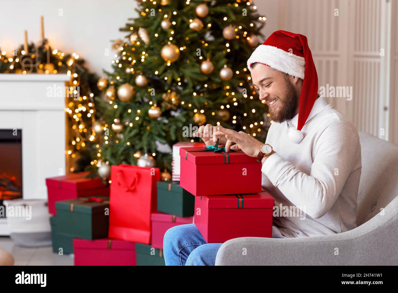 Handsome man opening Christmas gift at home Stock Photo - Alamy