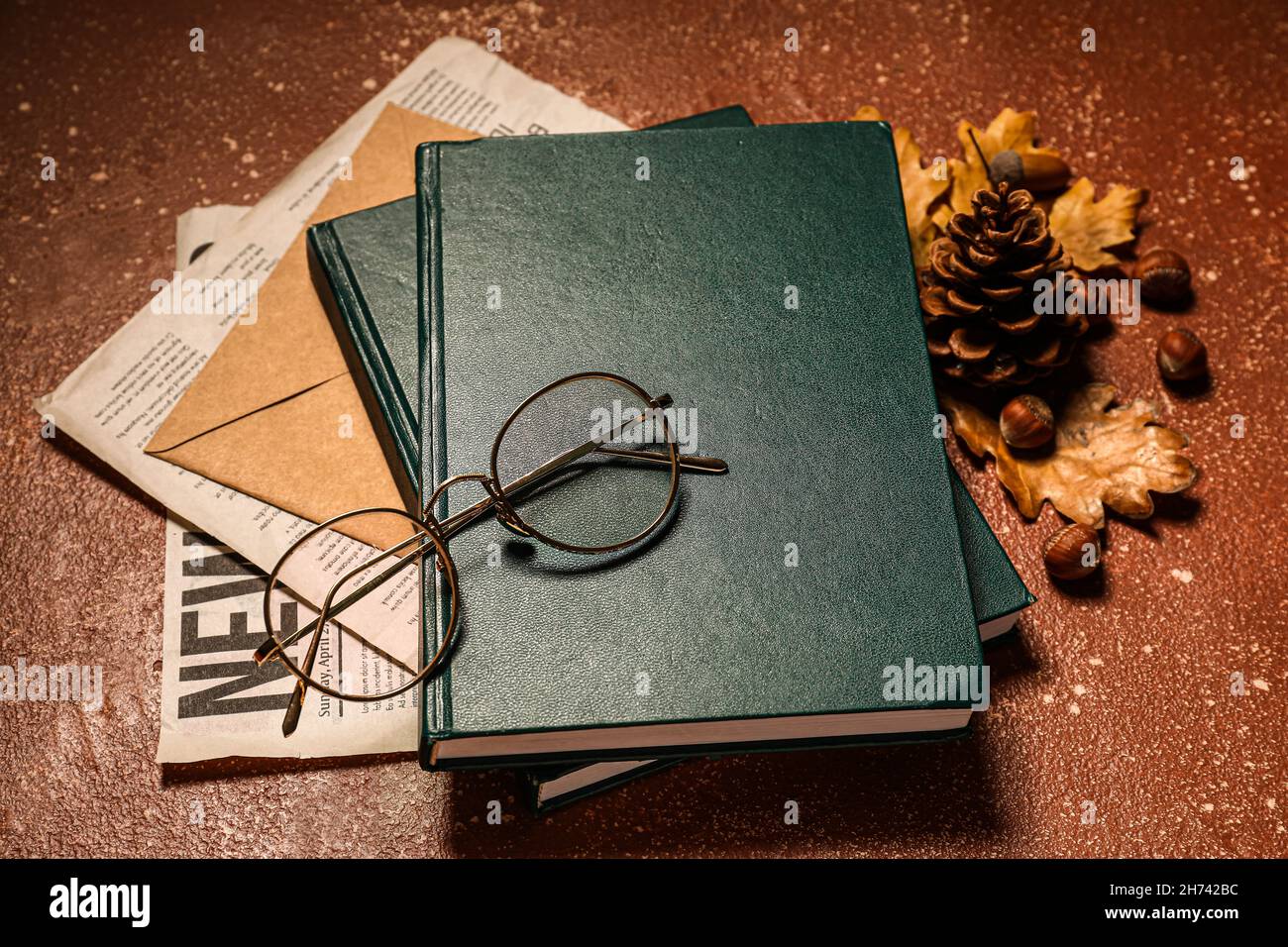 Stack of books, newspaper, envelope, eyeglasses and autumn decor on ...
