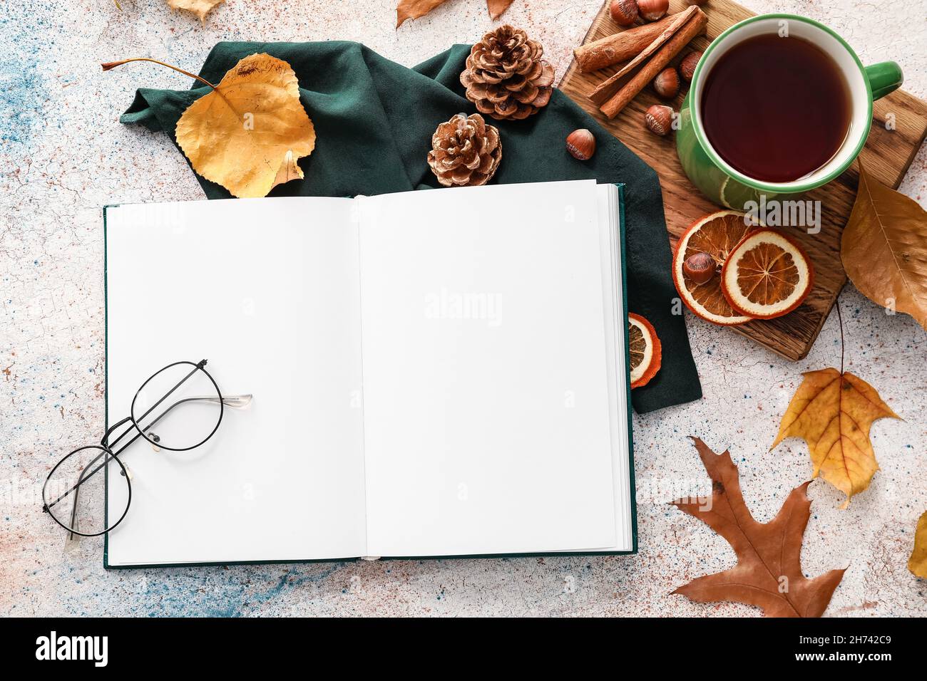 Opened book with blank pages, eyeglasses, cup of tea and autumn decor ...