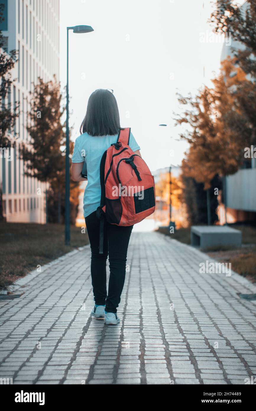 College campus student walking through college premises with backpack ...