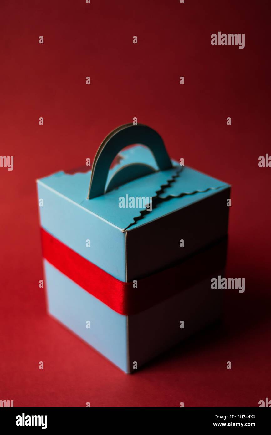 White gift box with handles and a red horizontal bow isolated on a red ...