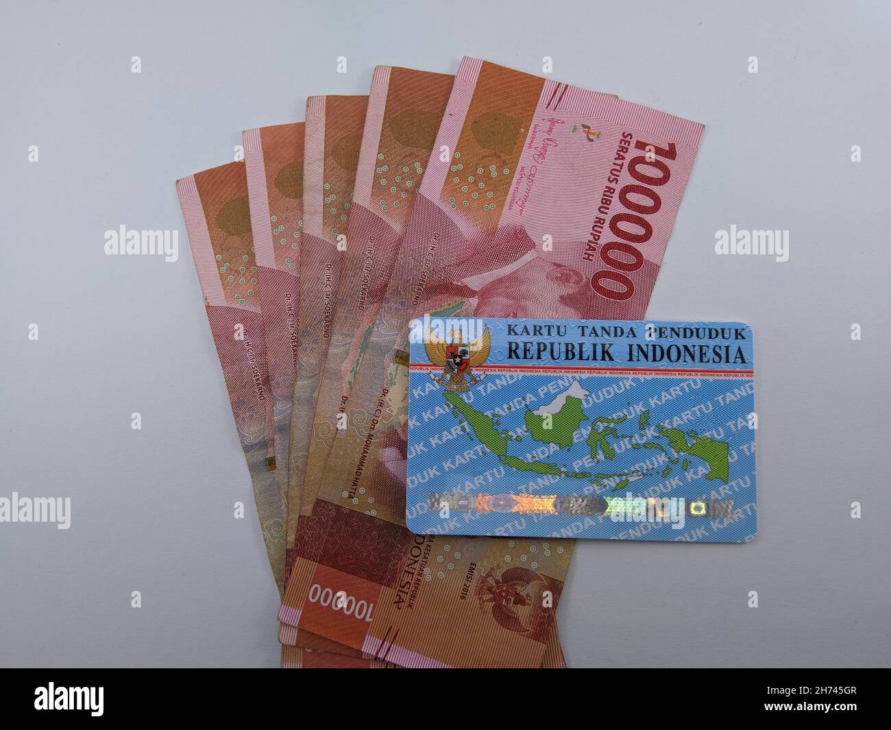Closeup of an Indonesian ID card with Indonesian paper bills on a white ...