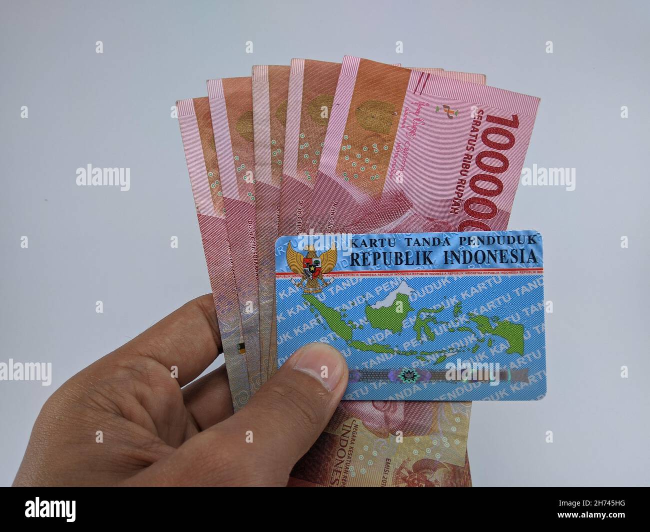 Closeup of male hands holding an Indonesian ID card with a bunch of ...