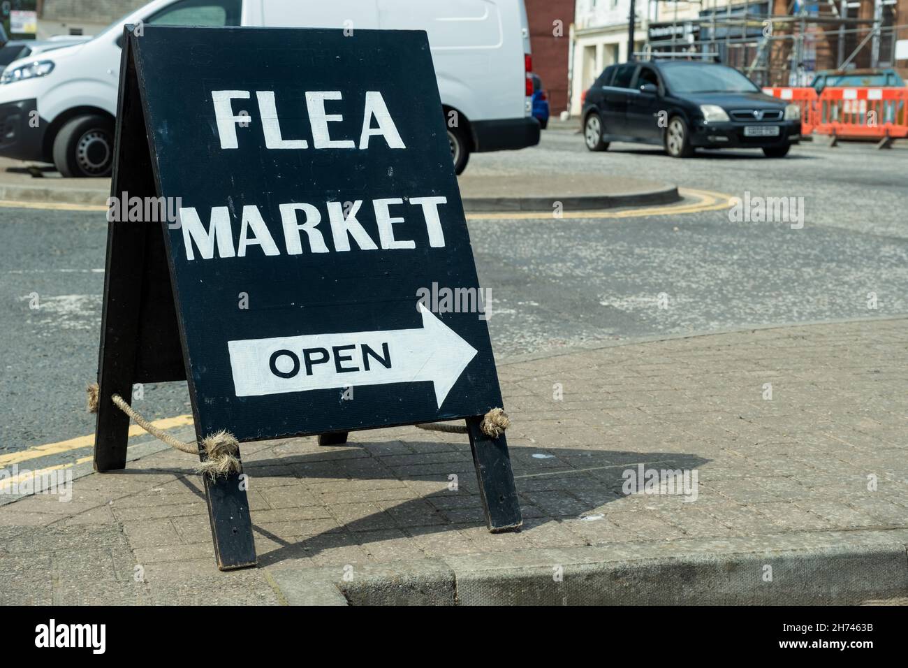 Black Flea Market sign stating that it is open and pointing the ...