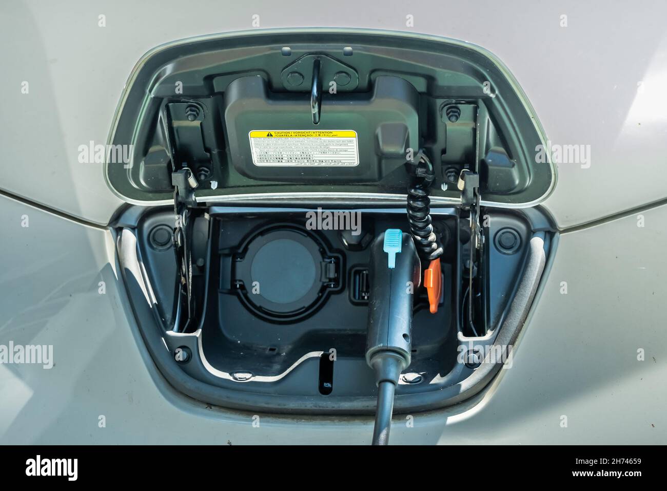 Electric vehicle with a front charging port plugged in and charging the ...