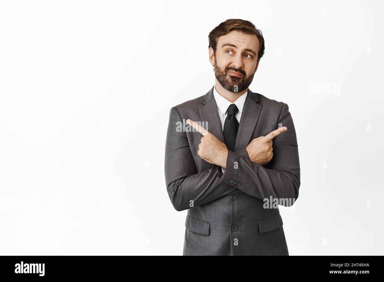 Confused businessman in grey suit troubled with choice, pointing ...