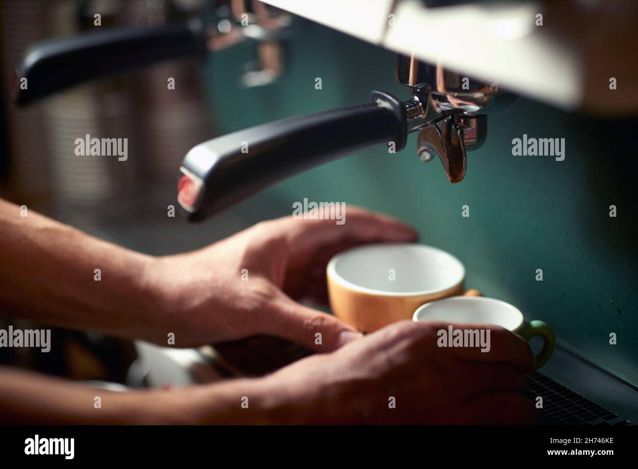 Barman putting cups into espresso apparatus to make an aromatic and ...