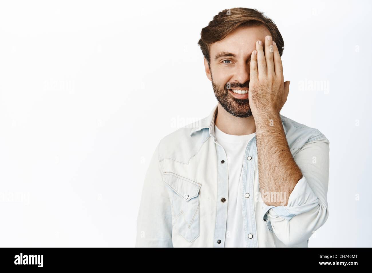 Portrait of bearded caucasian man covers half of face and smiles happy ...