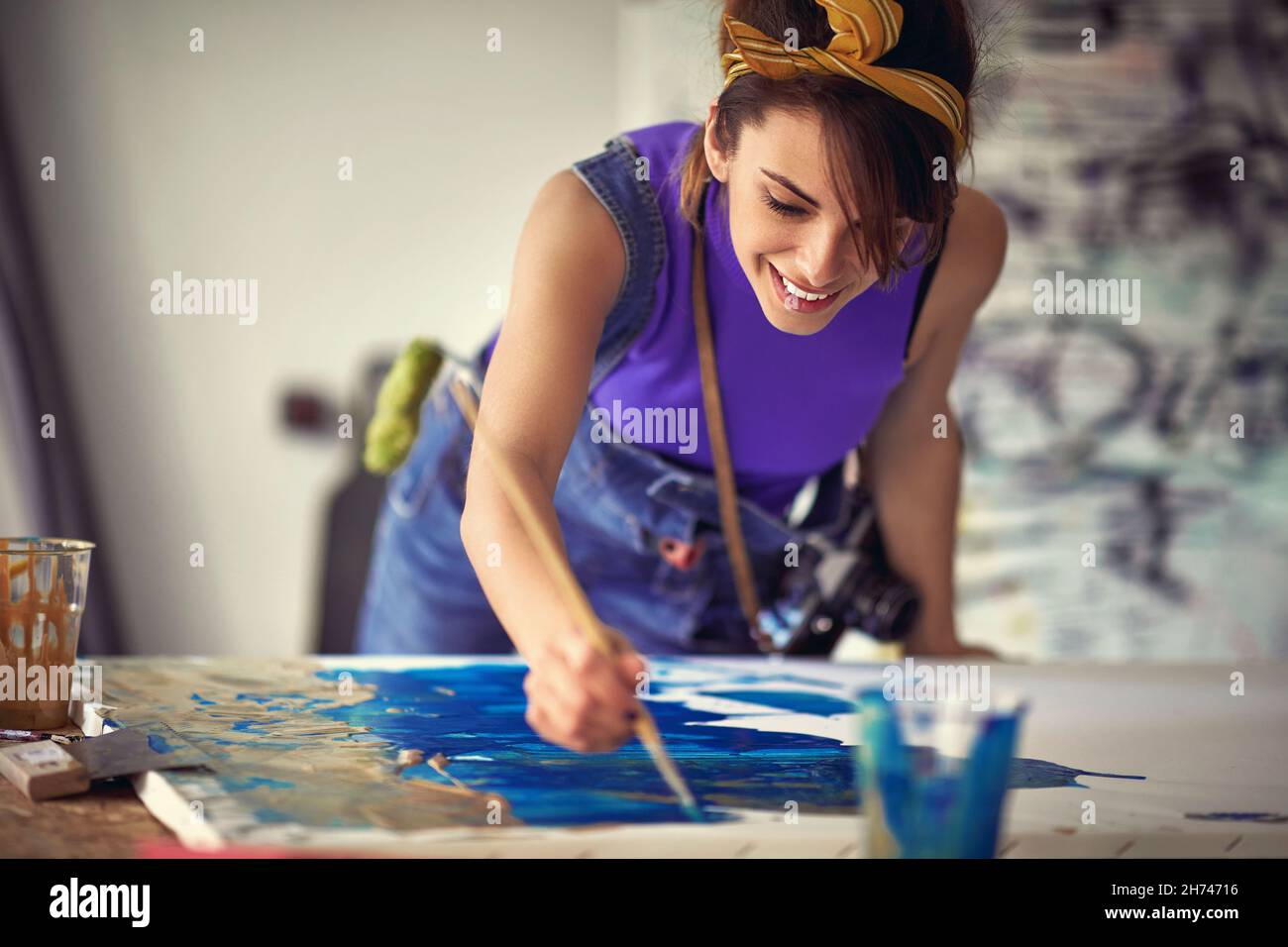 Close-up of a young female artist while working in a pleasant atmosphere in her studio. Art ...