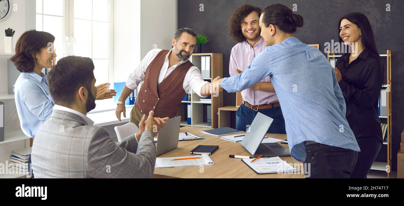 Two happy people making a deal and shaking hands in a business meeting ...
