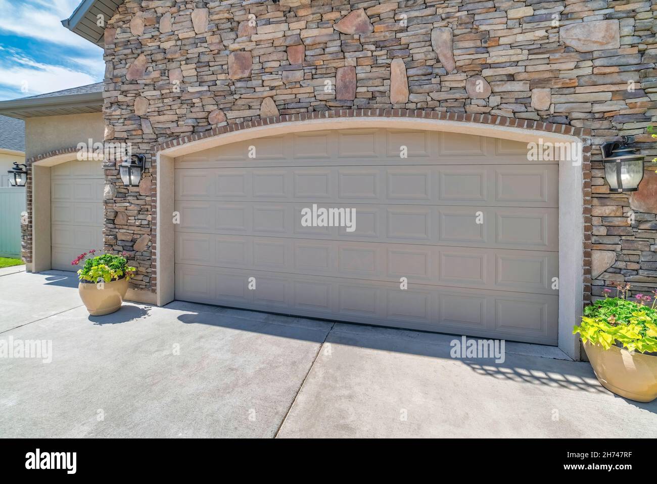 Two beige sectional garage doors with arched bricks door opening ...