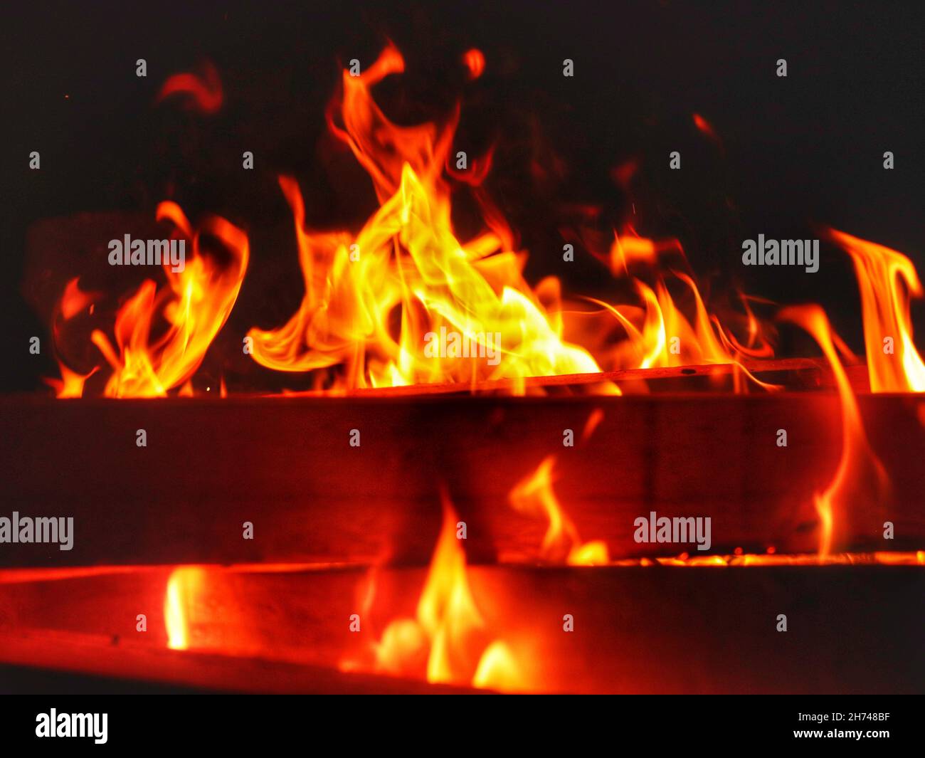 Closeup of a beautiful bright fireplace with red hot flames coming out ...