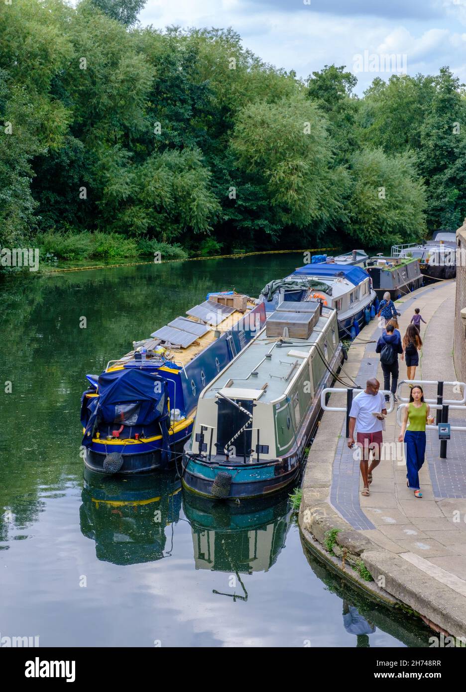 People walk along Regent’s Canal tow path on the north bank, with long ...