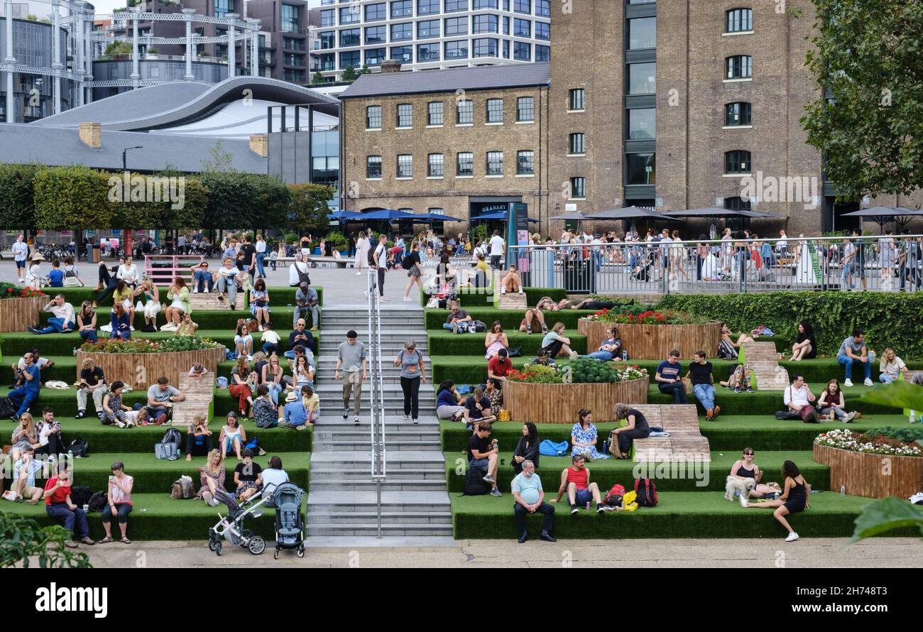 People relax on wide green steps next to Regent's Canal at Granary ...