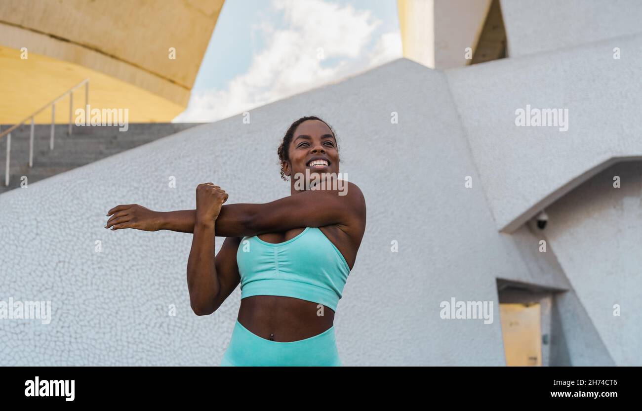 Young African woman doing stretching before workout session in the city ...