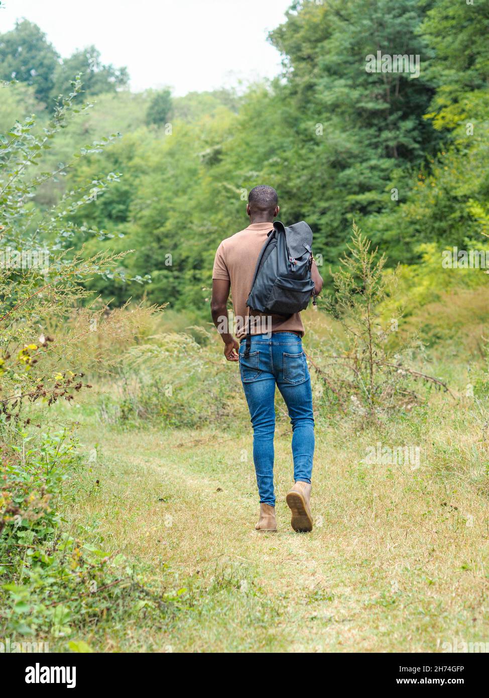 Back view of an African tall man in stylish clothes with a backpack ...