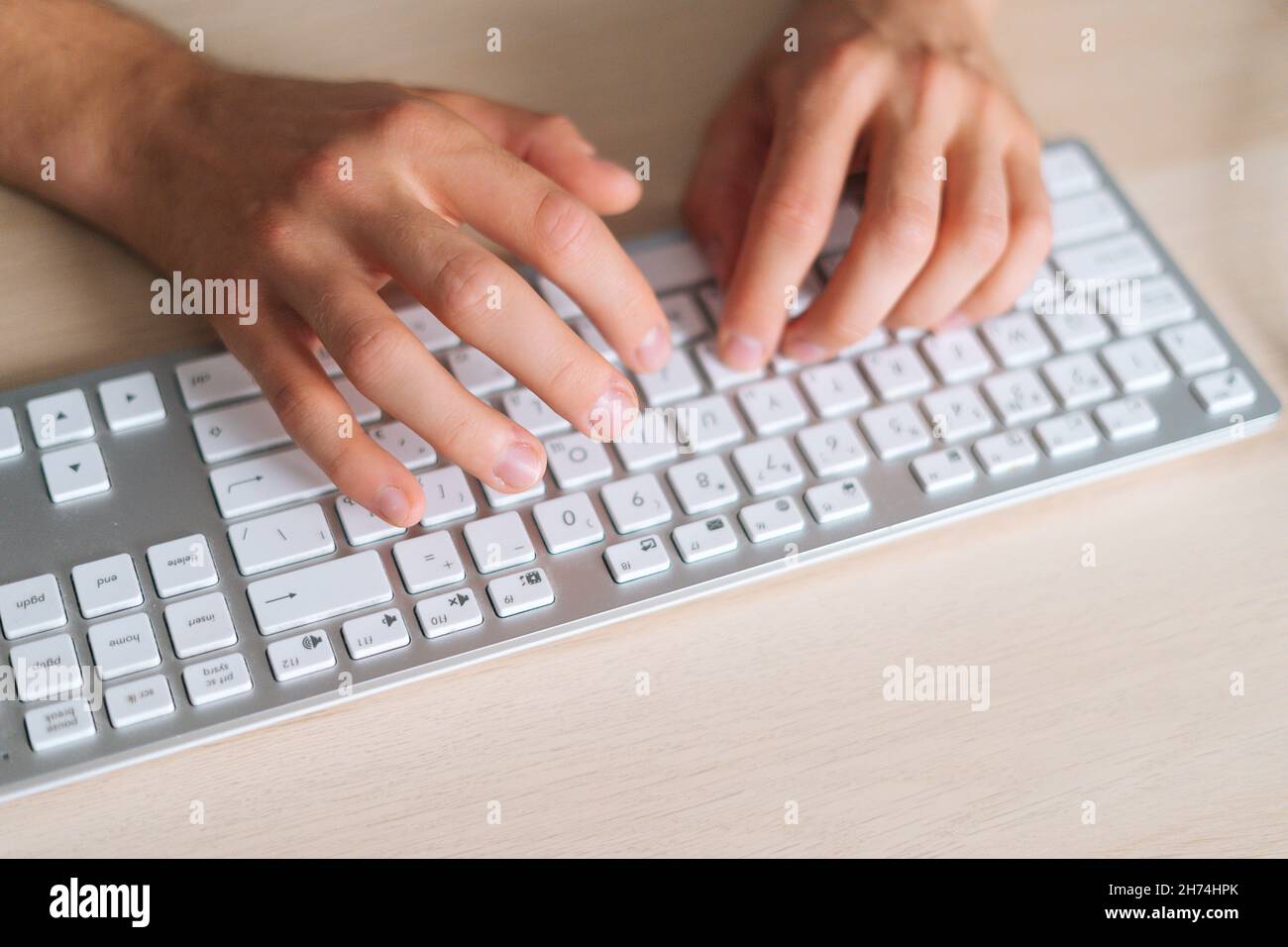 Close-up top view hands of unrecognizable business man using wireless computer keyboard sitting ...