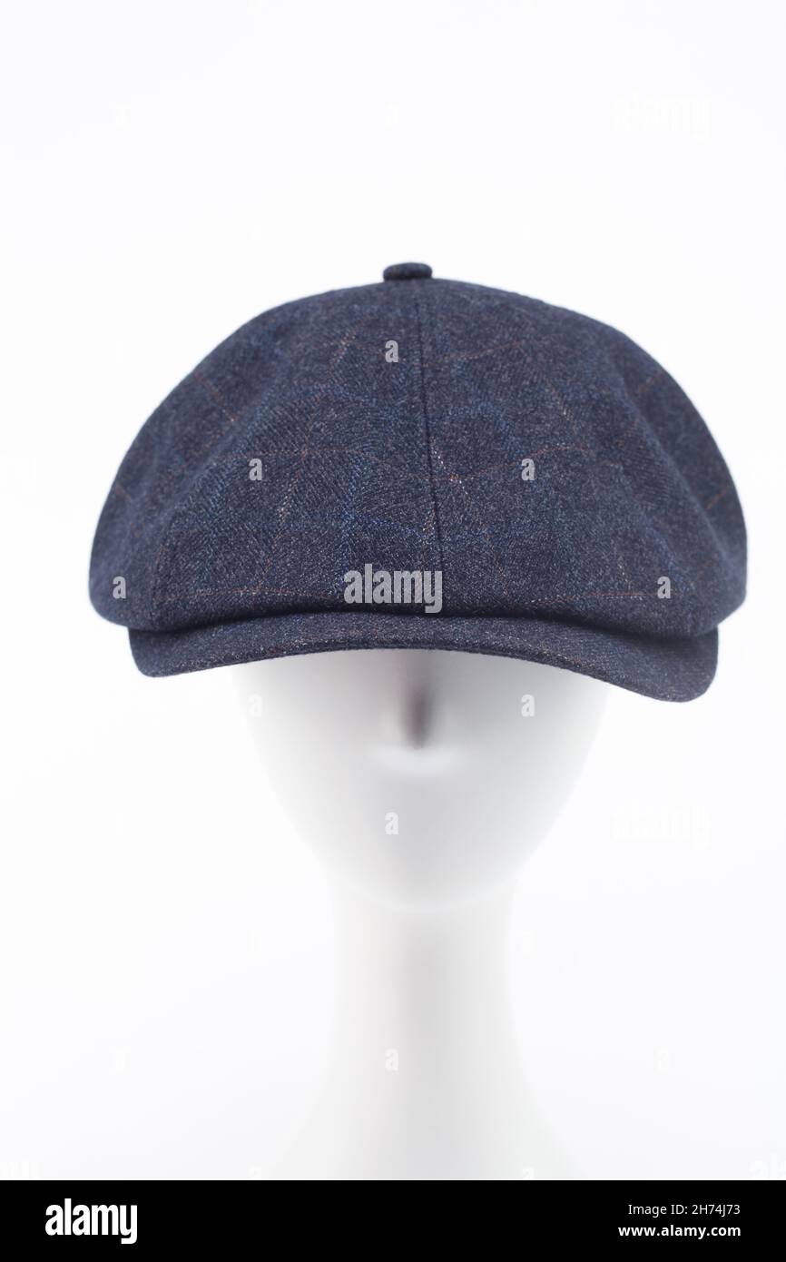 A dark blue checkered peaked cap with a visor on the head of a white ...