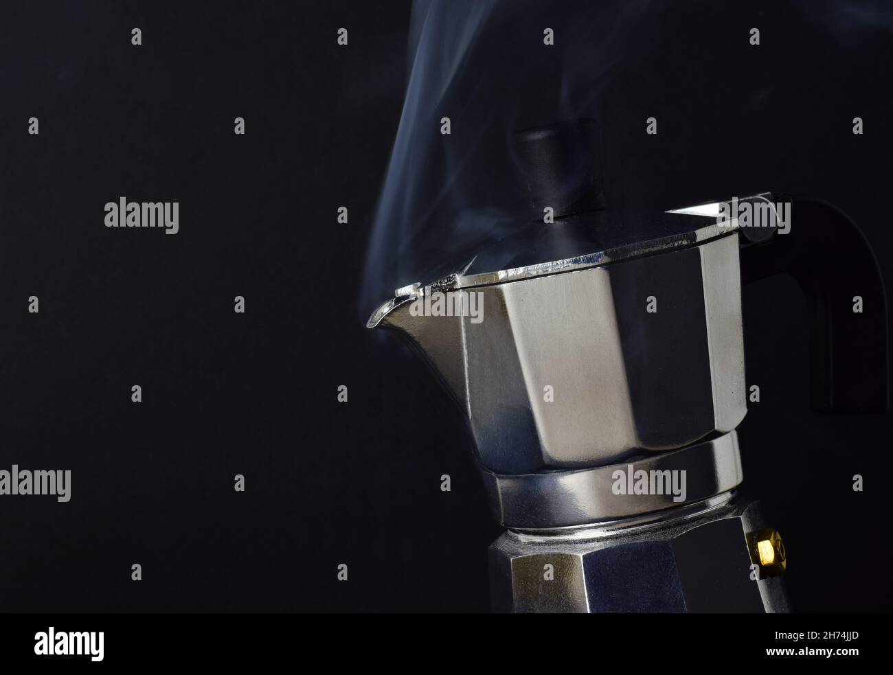 Steam of coffee boiling in a Moka pot in the black background with copy ...