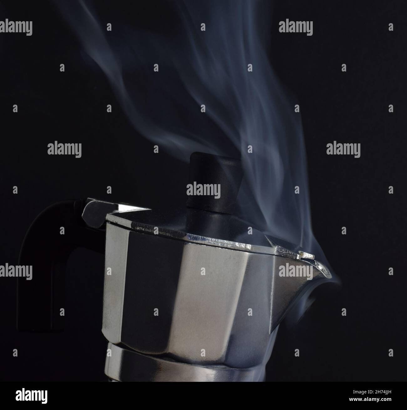 Steam of fresh coffee boiling in a Moka pot isolated in the black ...