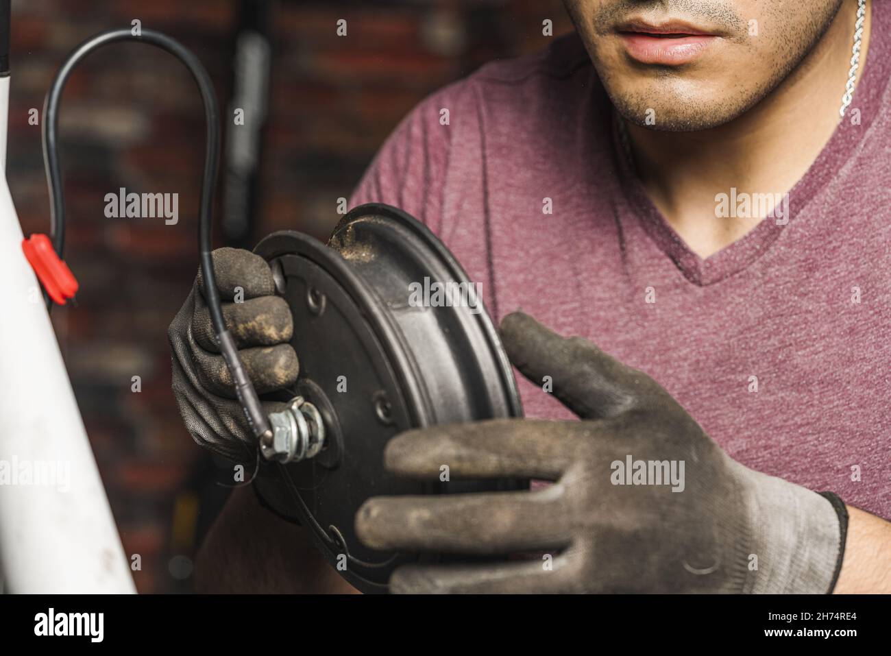 Up of a mechanic male holding a wheel rim of an electric scooter for ...